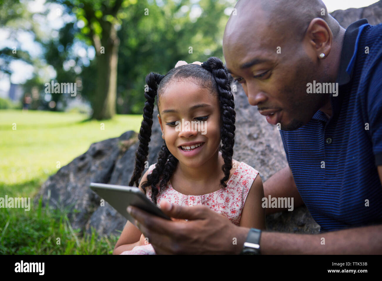 Close-up of father and daughter looking at tablet on sunny day Stock ...