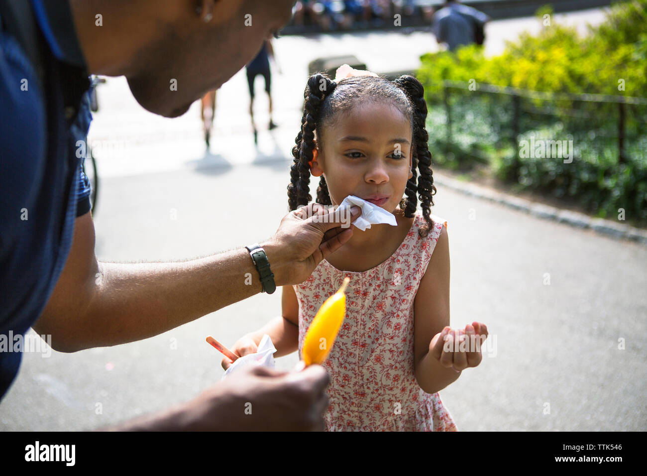 Father cleaning face of daughter with tissue at park Stock Photo - Alamy