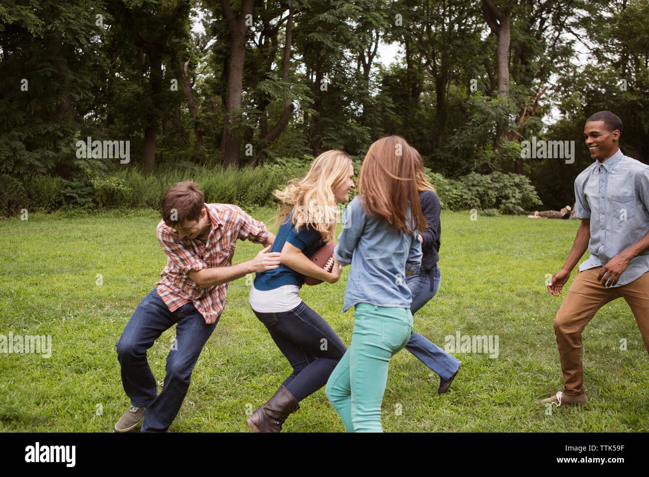 Cheerful friends playing football on grassy field Stock Photo - Alamy