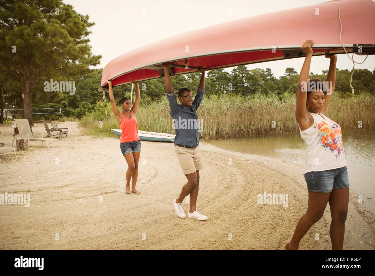 Friends carrying boat by lake Stock Photo - Alamy