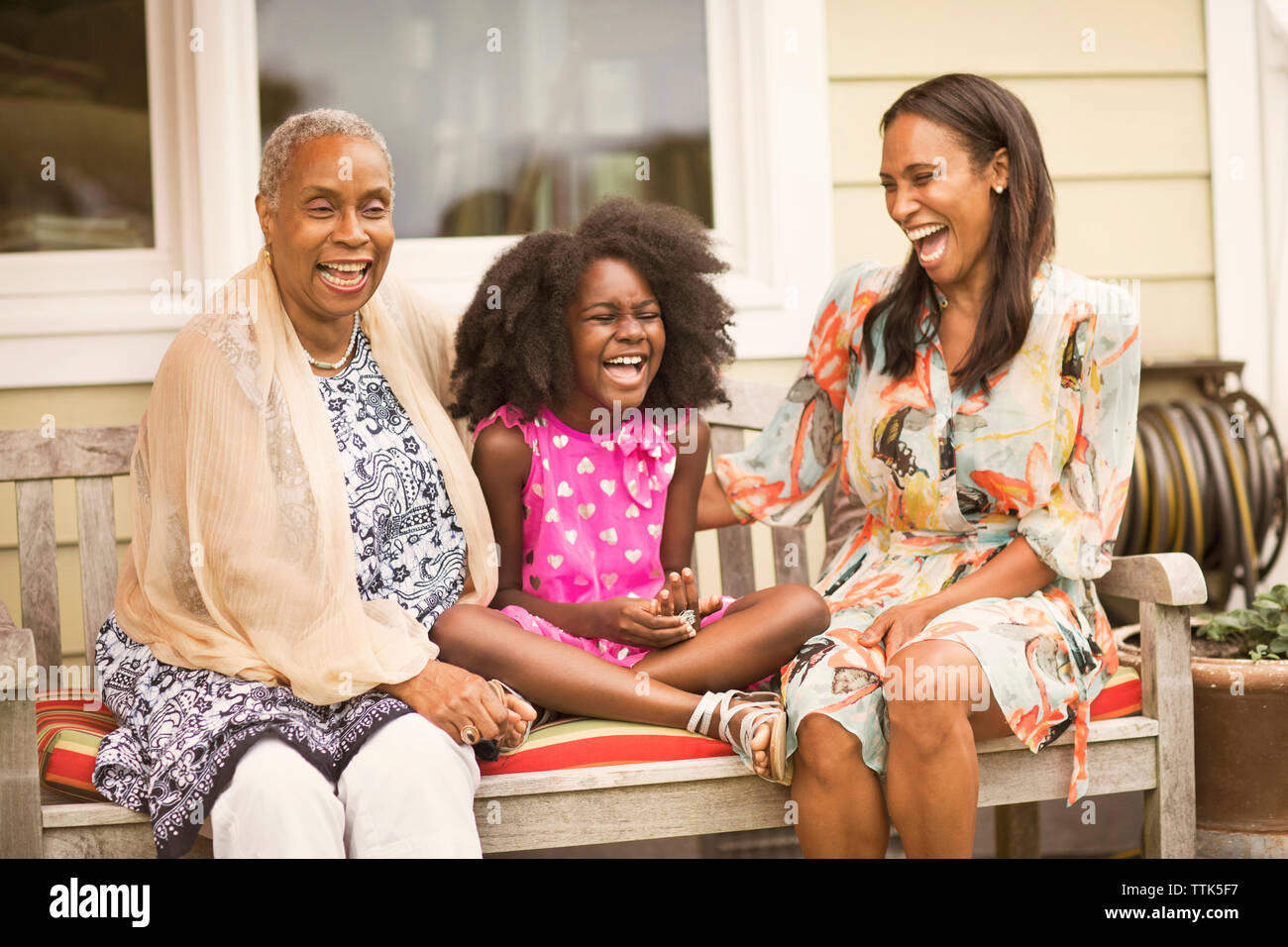 Happy family sitting on bench at patio Stock Photo - Alamy