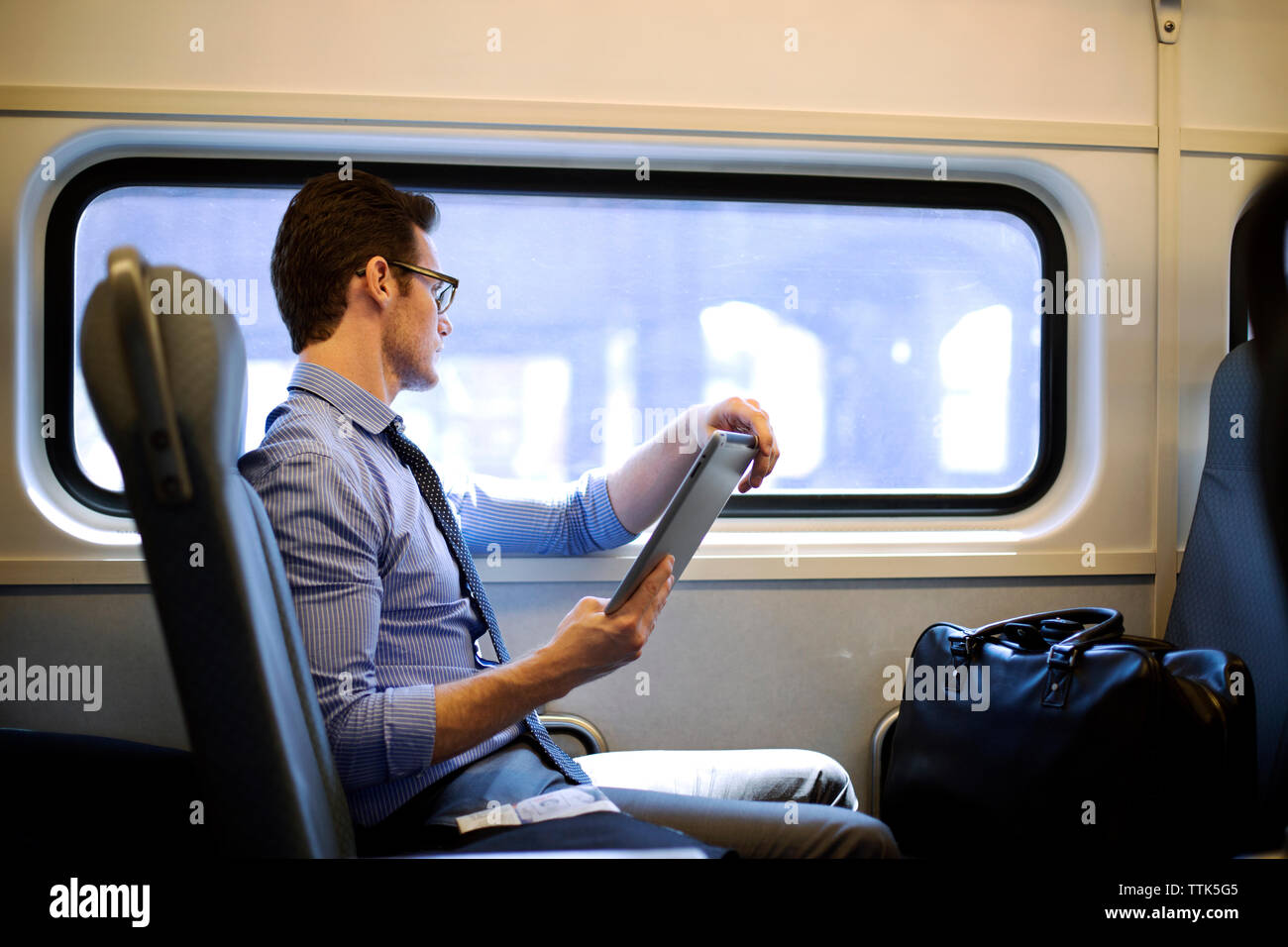 Side view of businessman holding tablet computer while traveling in ...
