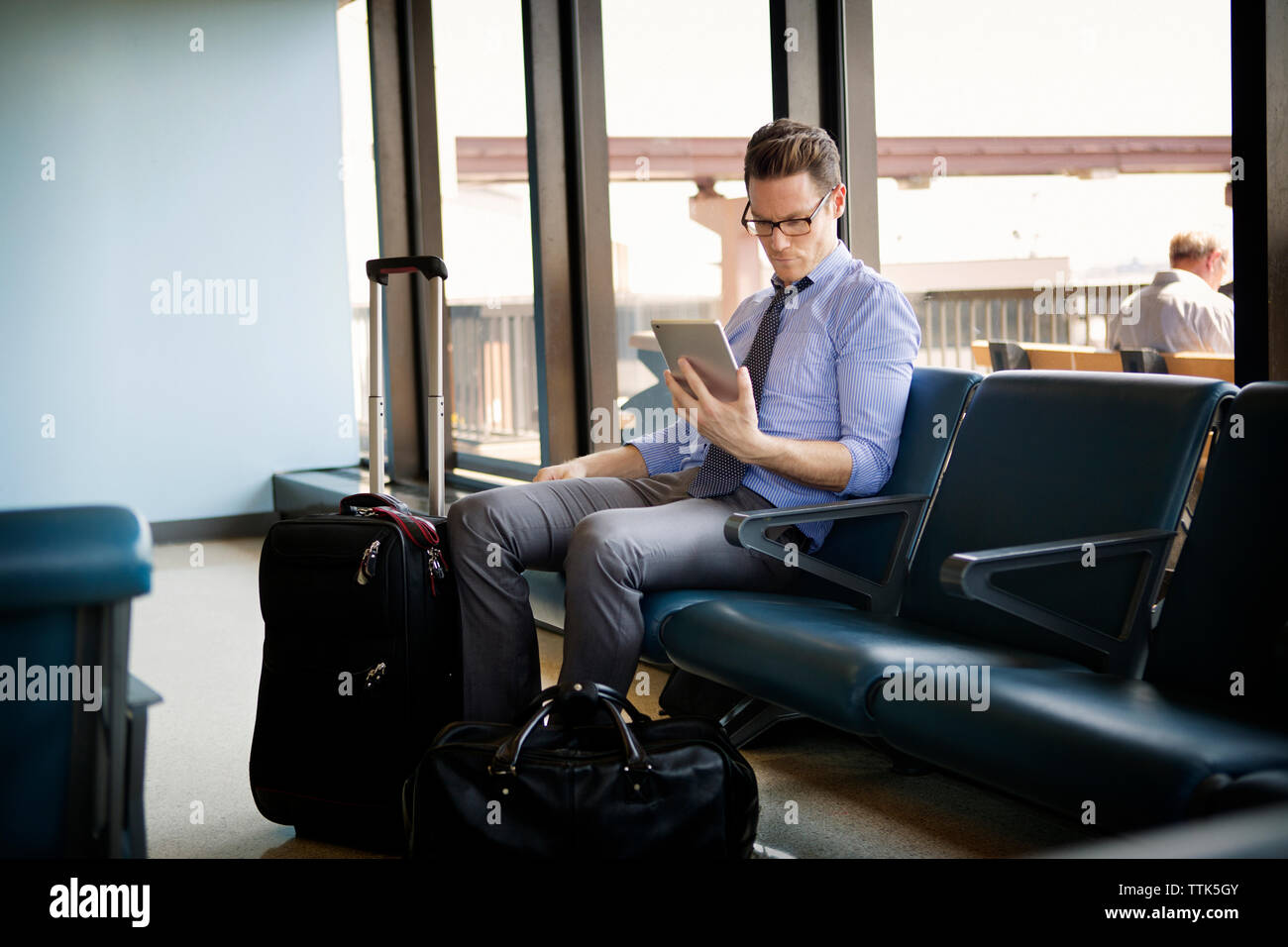 businessman using tablet computer while sitting in waiting area at ...