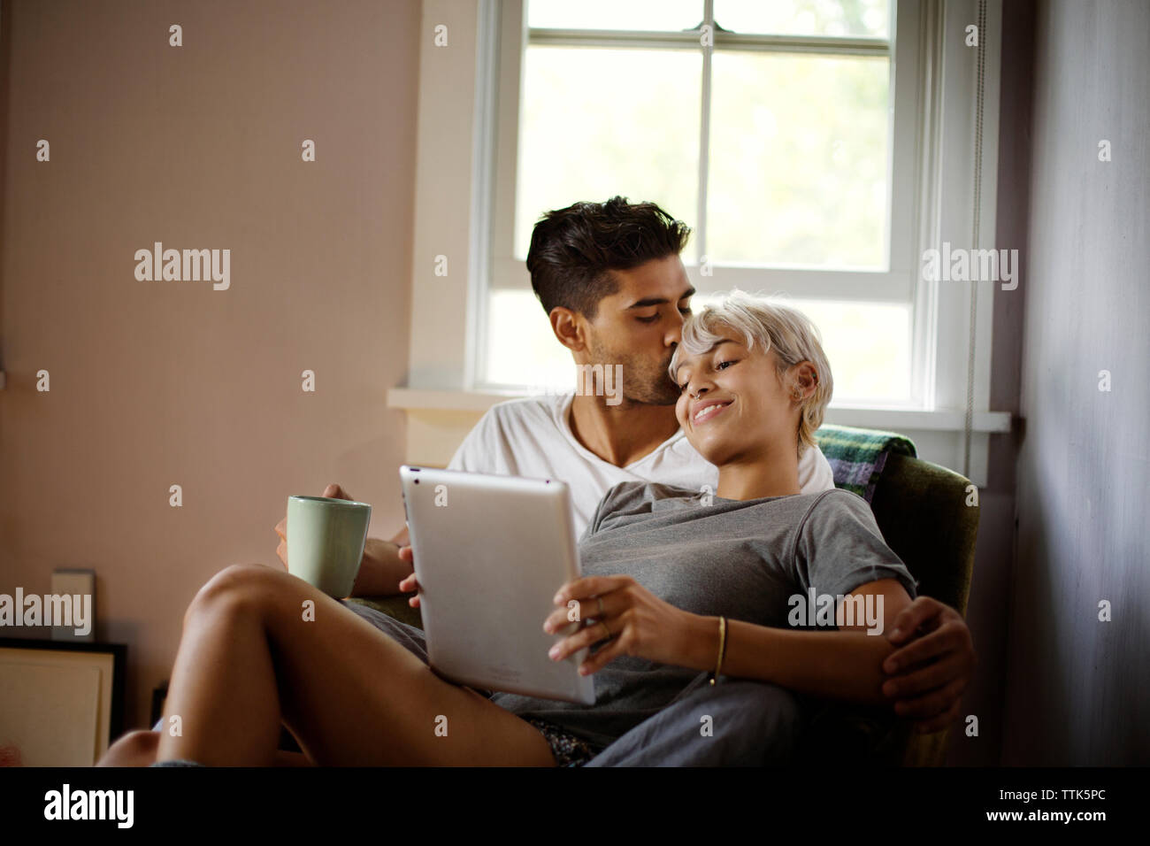 Man kissing woman using tablet computer at home Stock Photo - Alamy