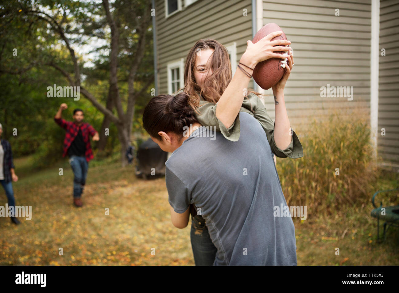 Couple playing football with friends on field Stock Photo - Alamy