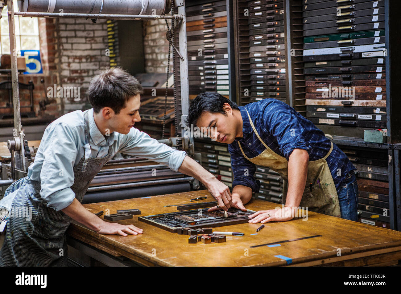 workers arranging letterpress on workbench at workshop Stock Photo - Alamy