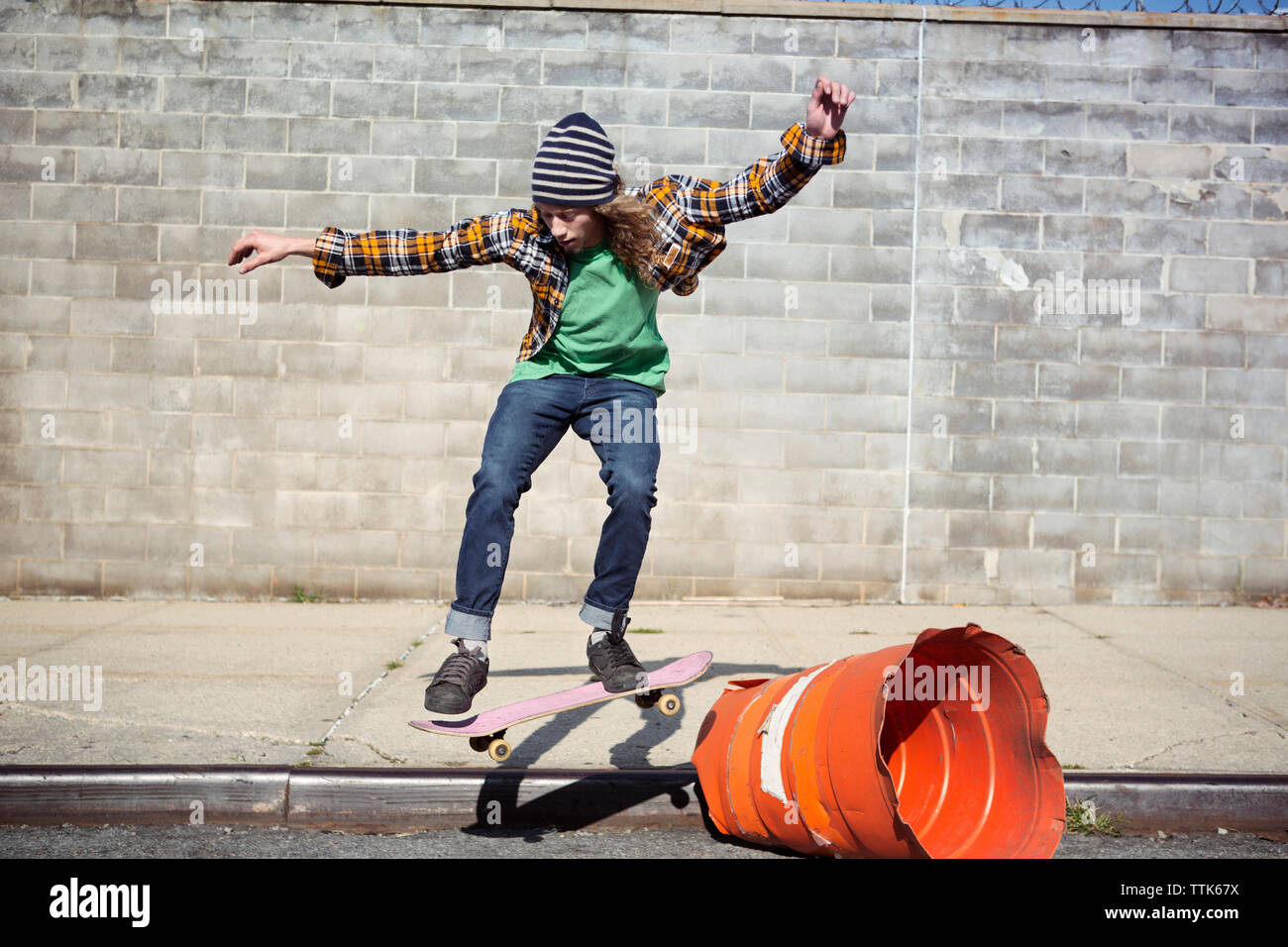 Man performing skateboard stunt over barrel on street Stock Photo - Alamy