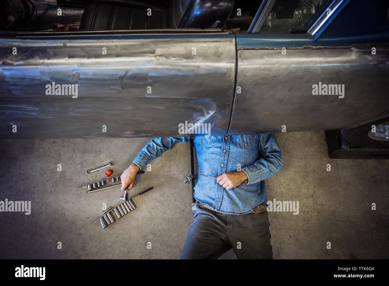 Overhead view of mechanic working under car in auto repair shop Stock ...