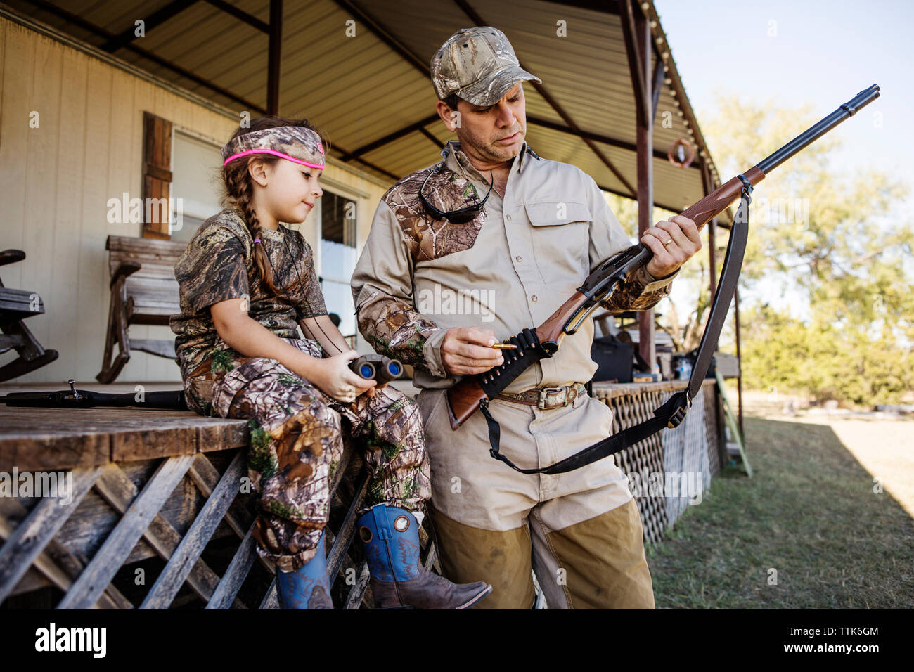 Father holding rifle while daughter sitting on porch Stock Photo - Alamy