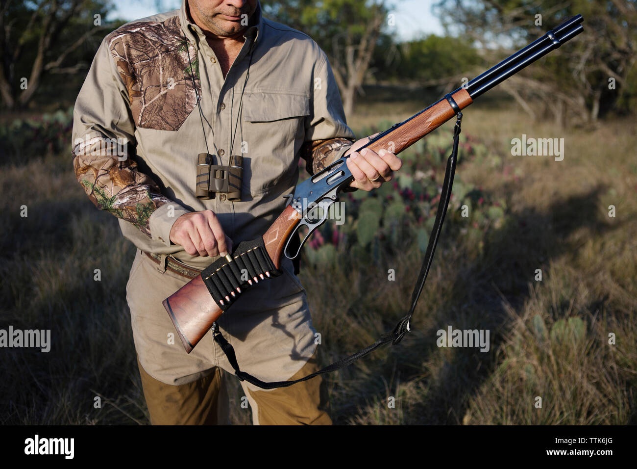Midsection of man loading bullet in rifle on grassy field Stock Photo ...
