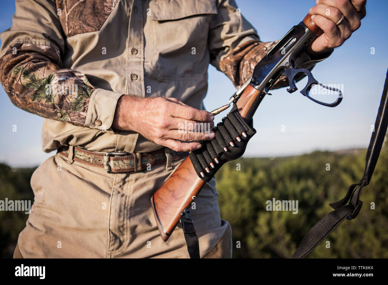Midsection of hunter loading bullet in rifle Stock Photo - Alamy