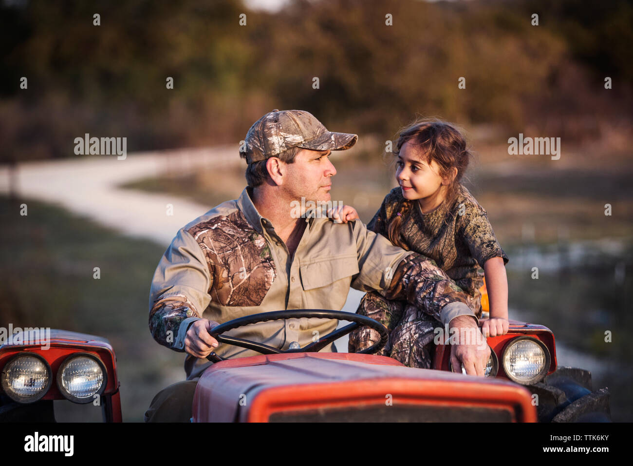 Man driving tractor while looking at daughter Stock Photo - Alamy