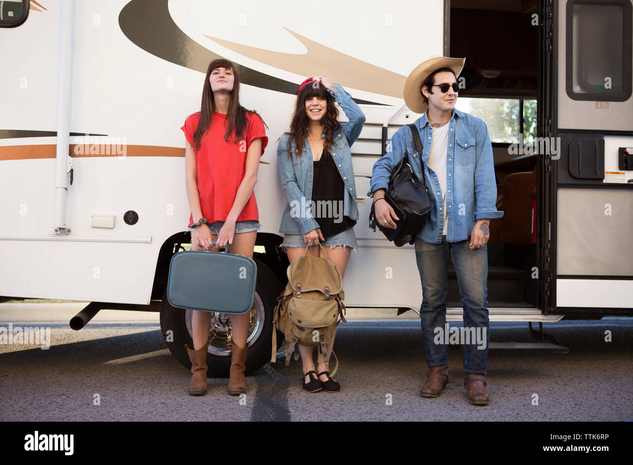 Friends carrying luggage while standing against camper van Stock Photo ...