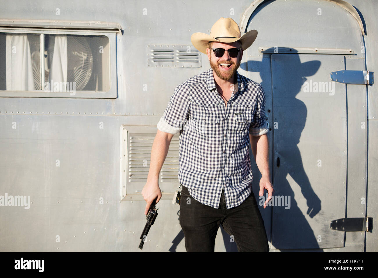 Cheerful man holding gun while standing against camper van Stock Photo ...
