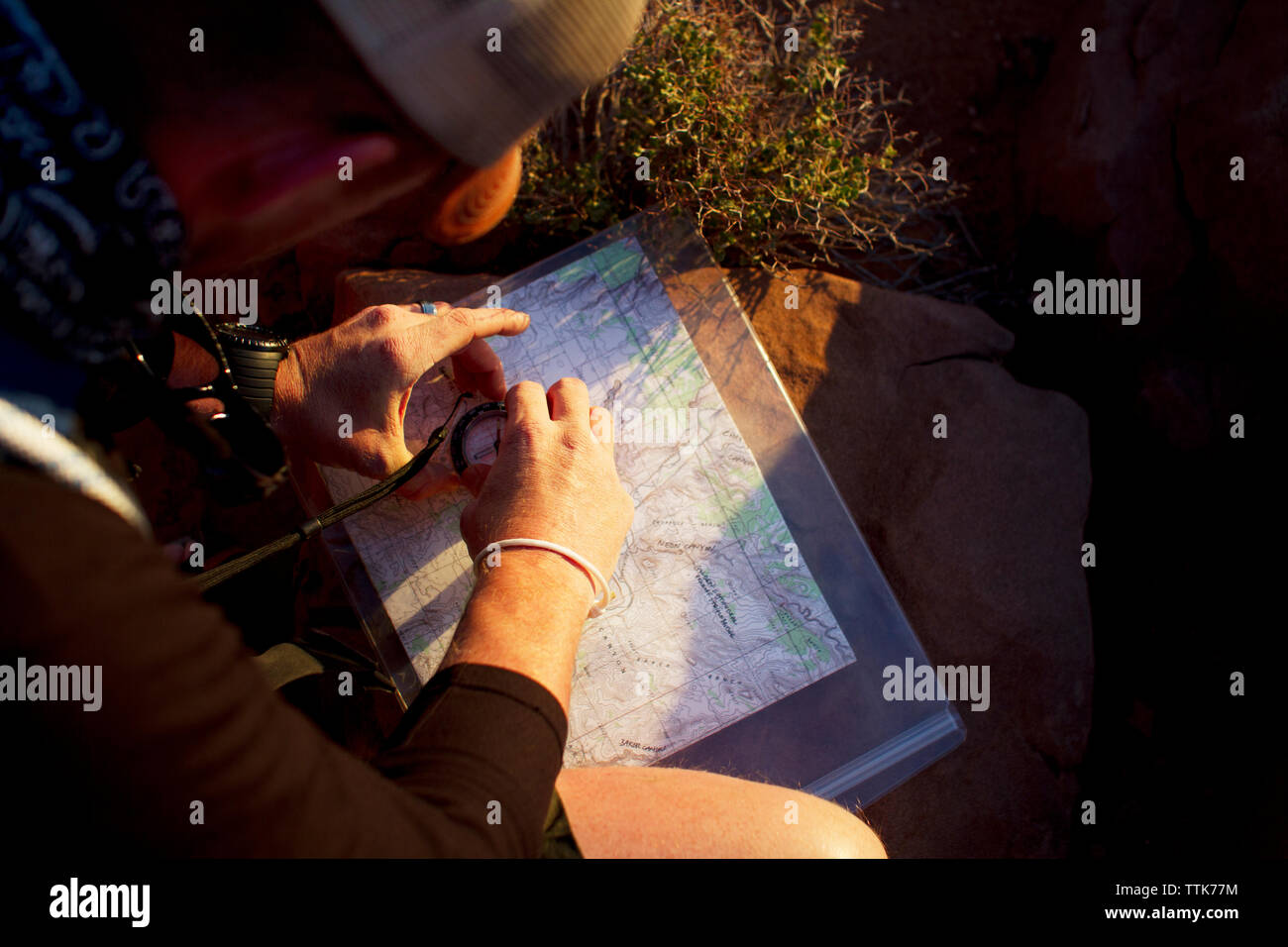 Overhead view of man using navigational compass on map while sitting on ...