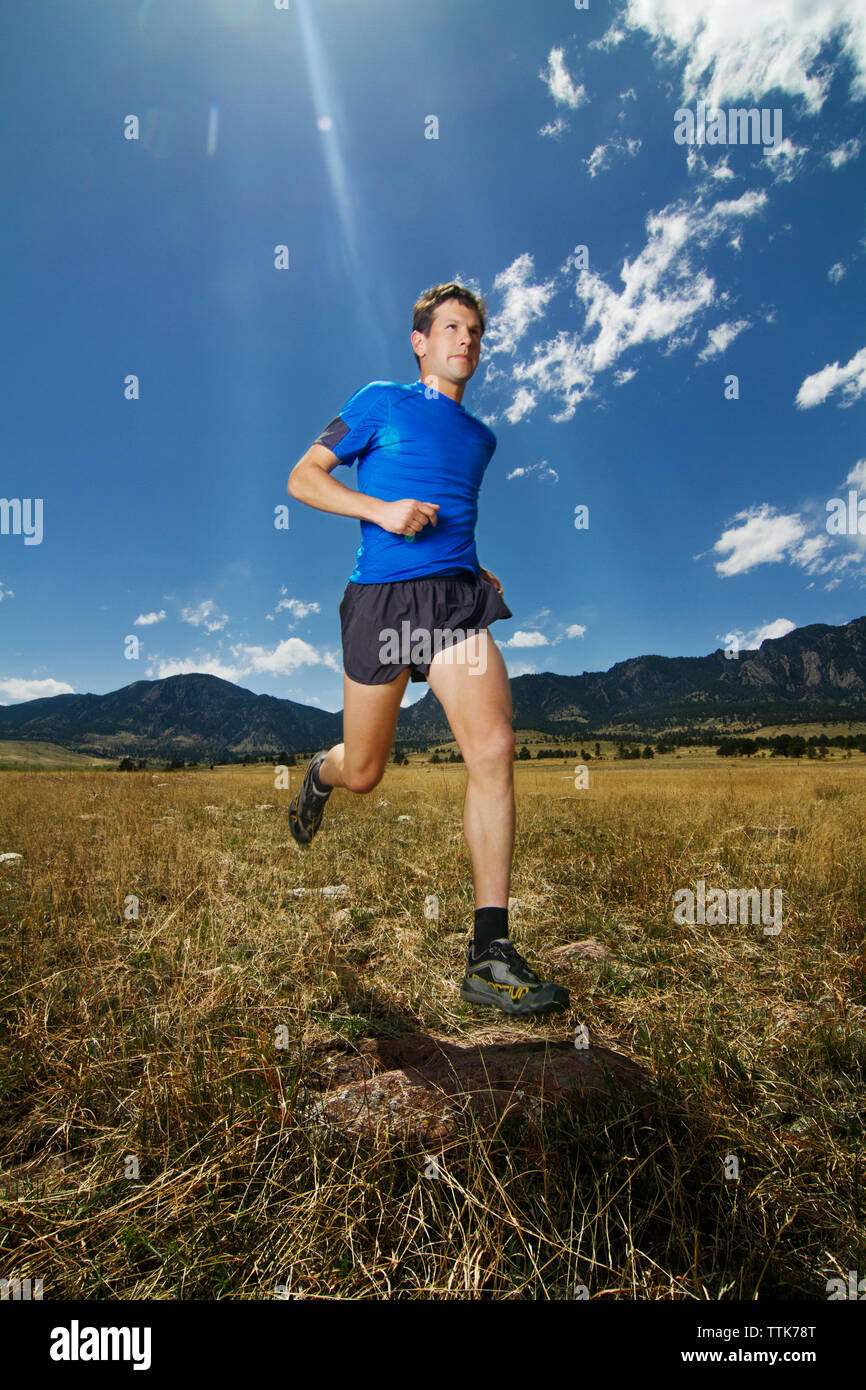 Low angel view of man running on grass field against sky Stock Photo ...