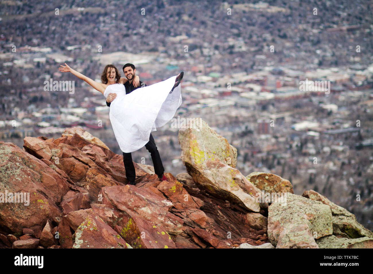 Man lifting bride while standing on rocky mountain Stock Photo - Alamy