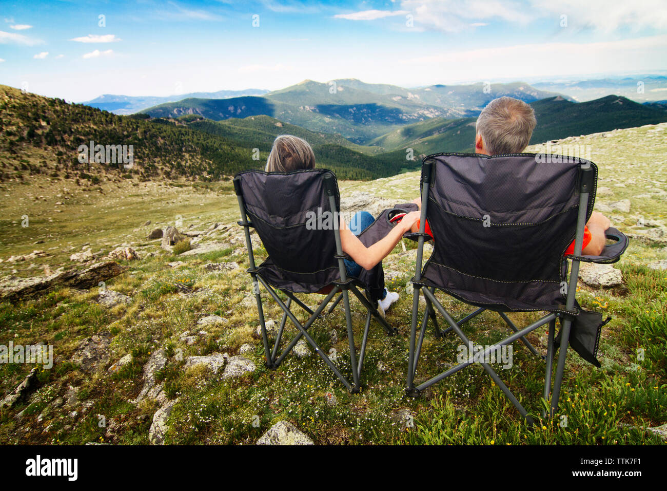 Rear view of couple sitting on chair against mountain Stock Photo - Alamy