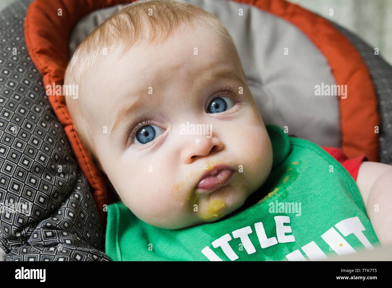 High angle view of baby boy with messy mouth sitting on high chair at ...
