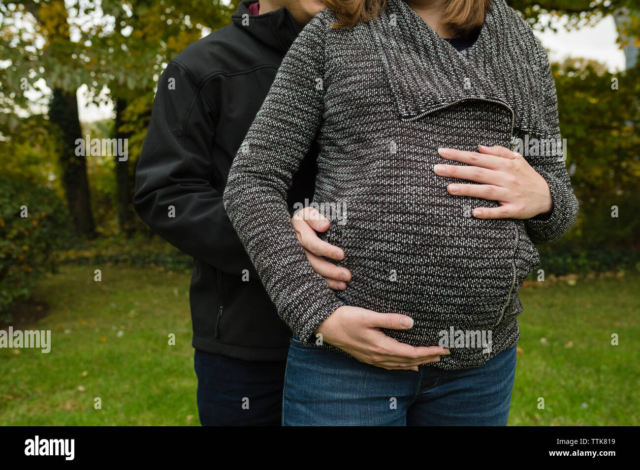 Midsection of expectant couple standing in park Stock Photo - Alamy