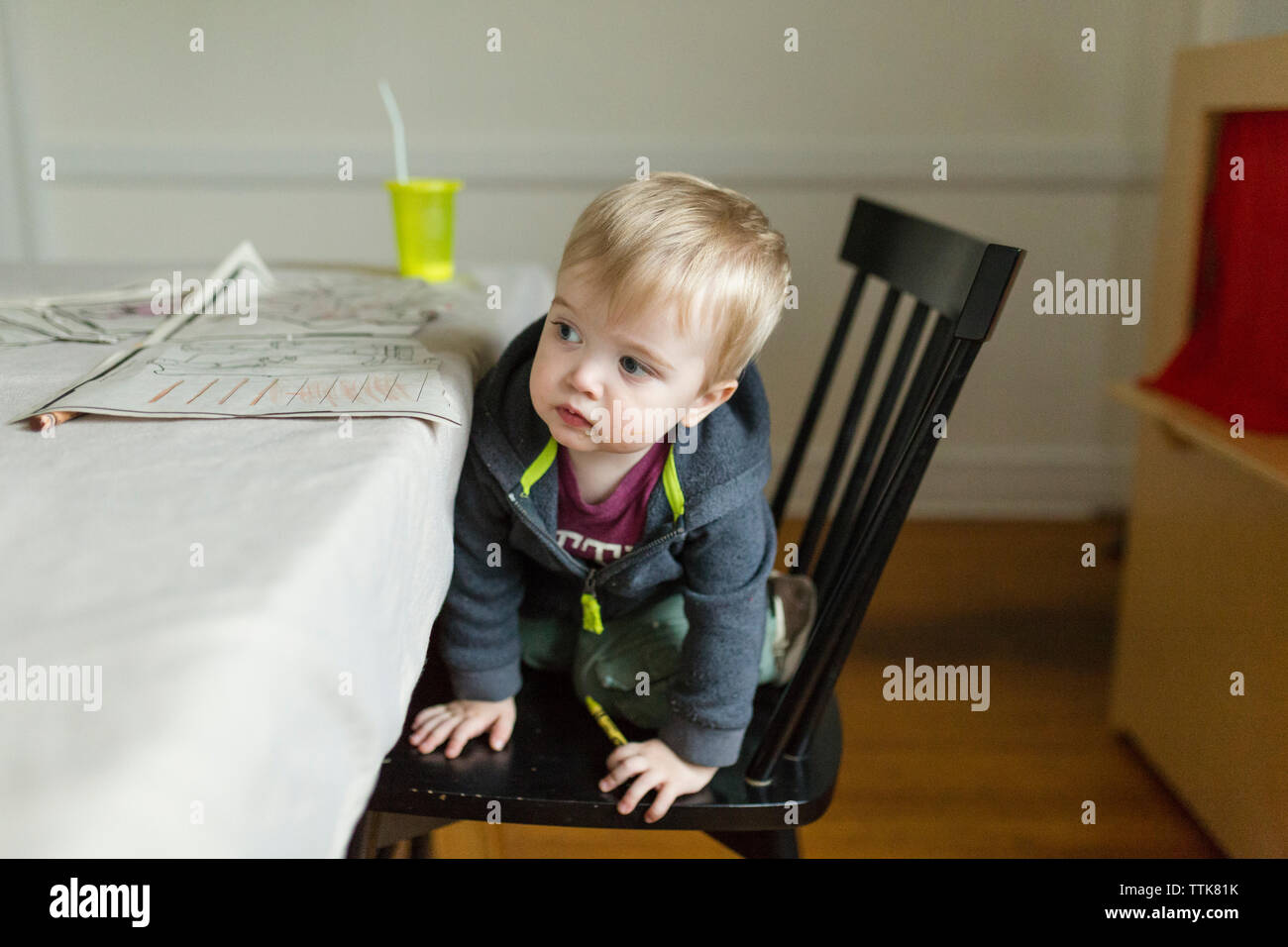 Toddler boy kneels on dining room chair while coloring Stock Photo - Alamy