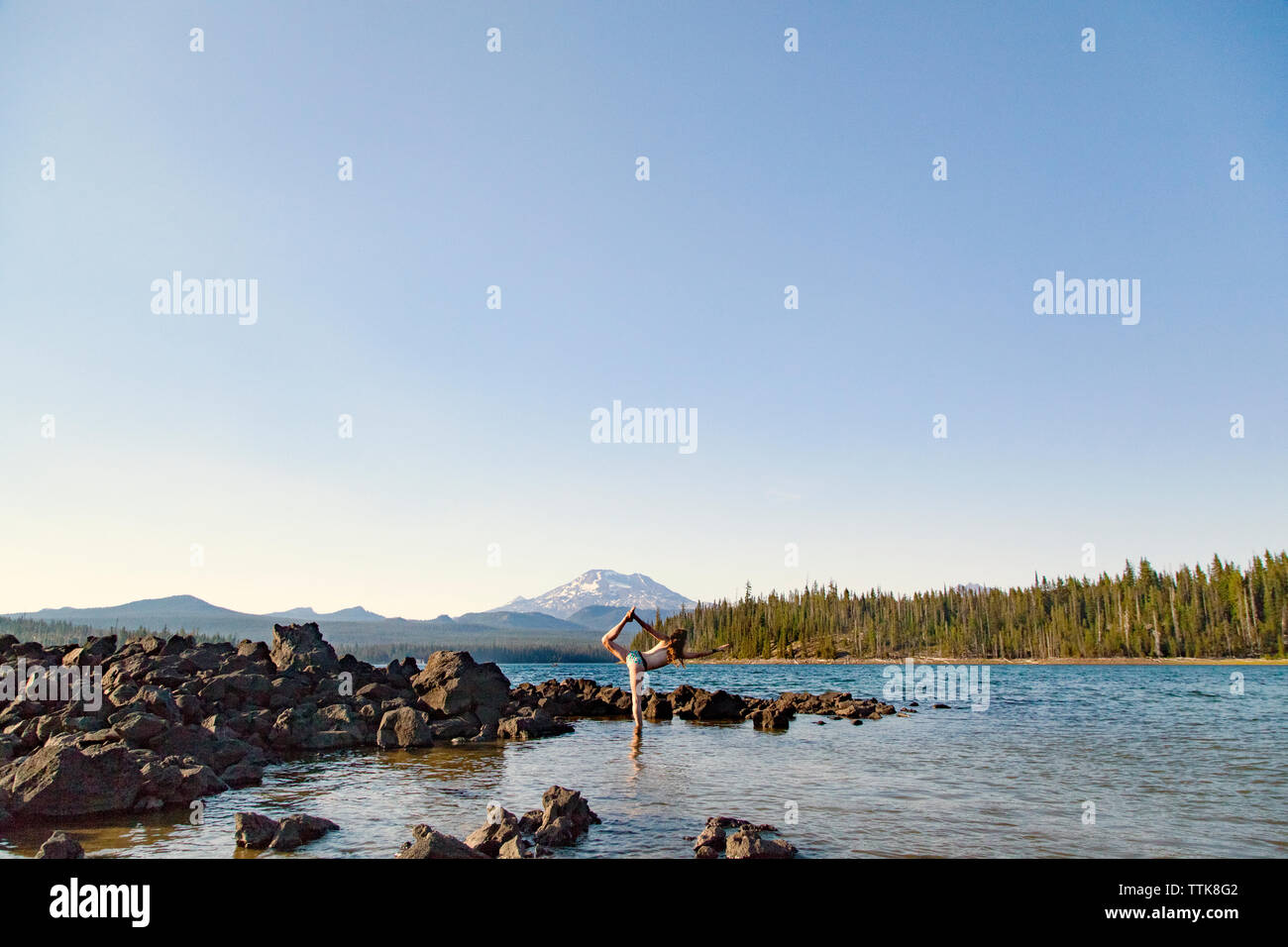 Woman standing on one leg at Elk Lake against clear sky Stock Photo - Alamy