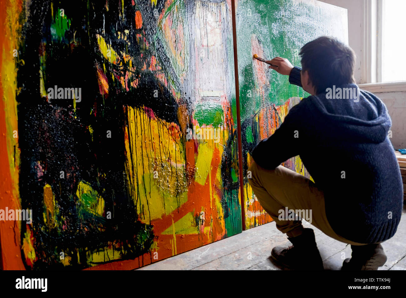 Full length of man painting while crouching on floor at home Stock ...
