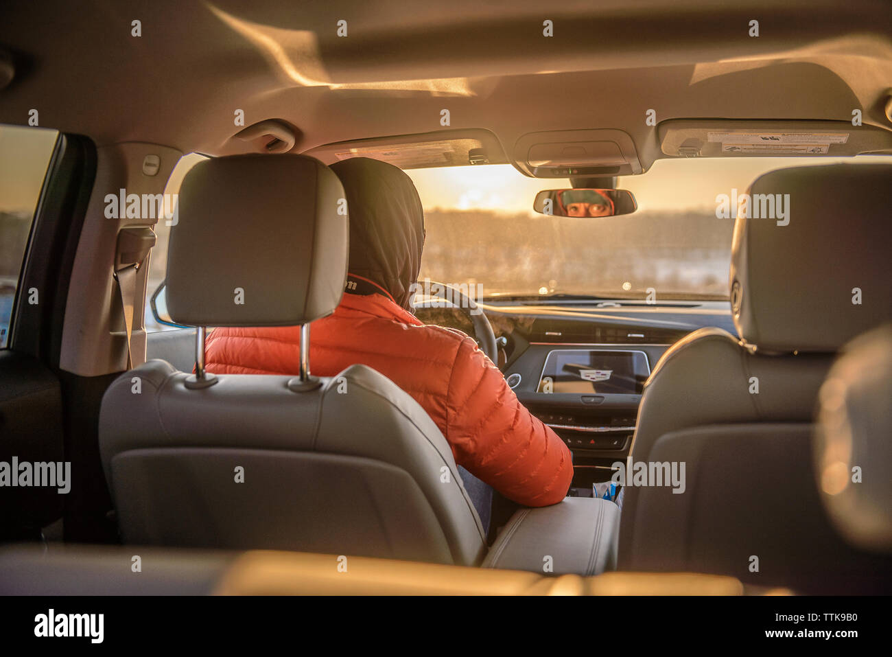 View of man parked with city skyline from inside luxury car at sunset ...