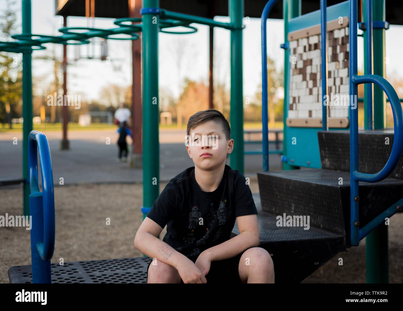 Sad boy looking away while sitting at playground Stock Photo - Alamy