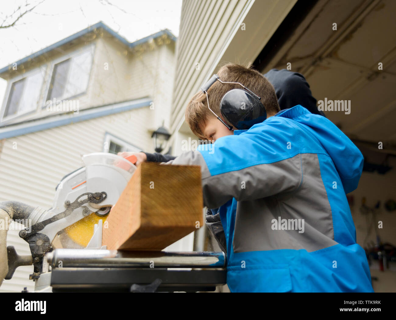 Side view of boy using ear protectors while working at backyard Stock ...