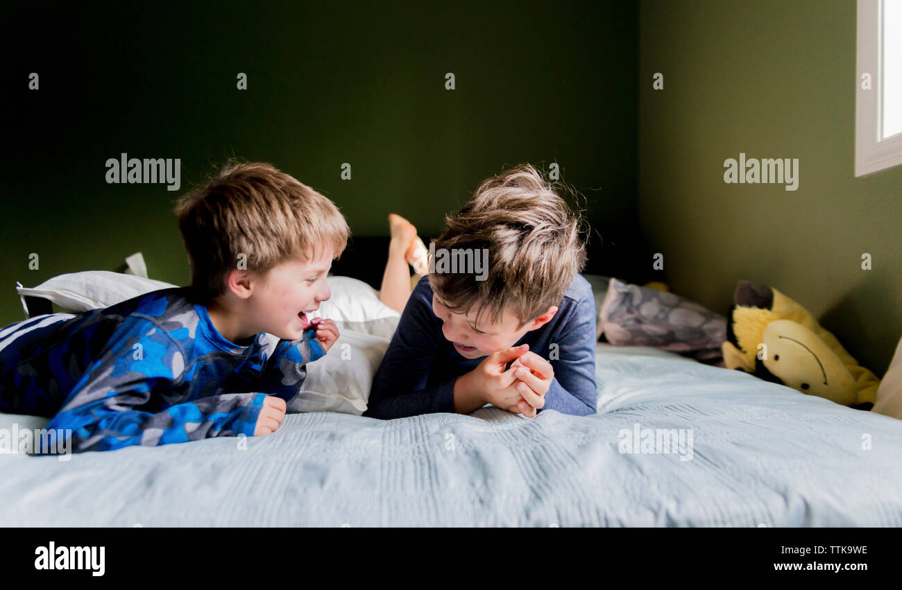 Happy brothers talking while lying on bed at home Stock Photo - Alamy