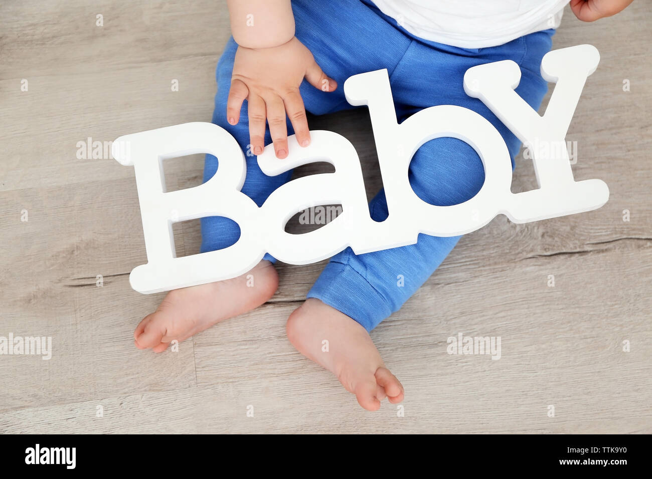 Baby boy playing with letters of the word baby on the floor Stock Photo ...