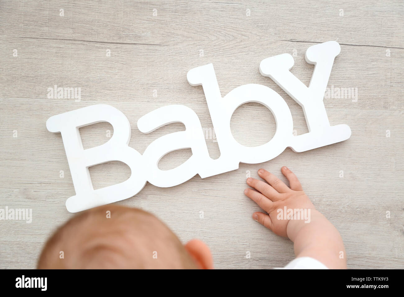 Baby boy playing with letters of the word baby on the floor Stock Photo ...
