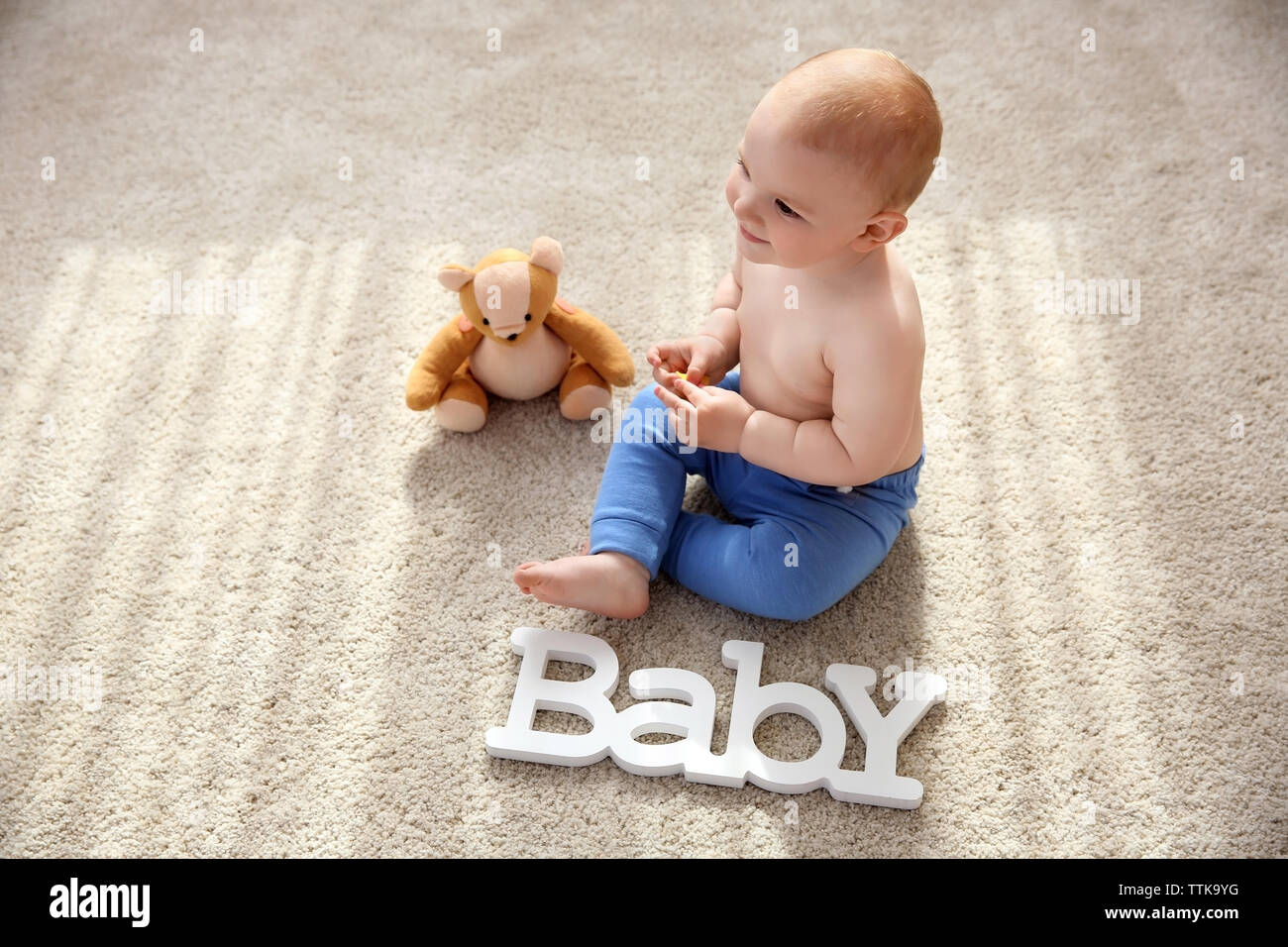 Baby boy playing with teddy bear on the floor Stock Photo - Alamy