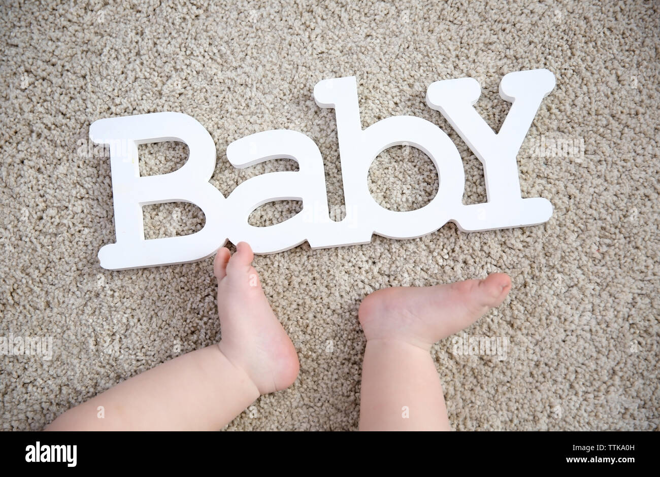 Baby legs and decorative word on the floor Stock Photo - Alamy