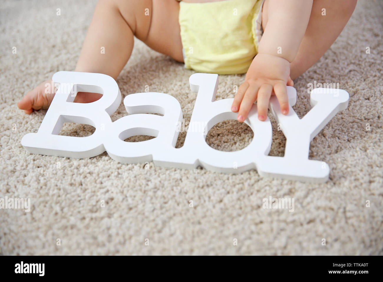 Baby legs and decorative word on the floor Stock Photo - Alamy