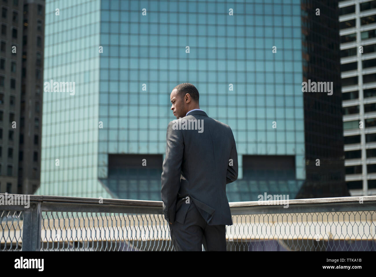Rear view of businessman standing against office buildings Stock Photo ...