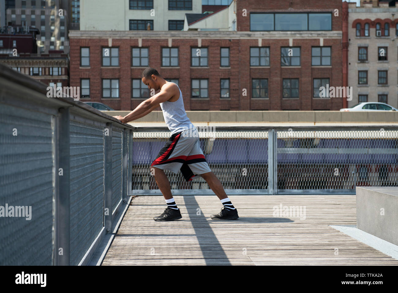 Side view of man leaning on railing at boardwalk against buildings ...