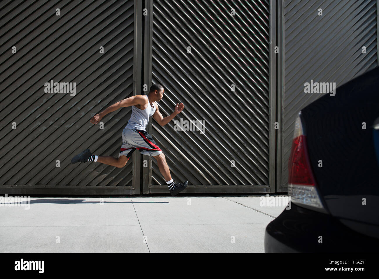 Side view of man running against wall Stock Photo - Alamy