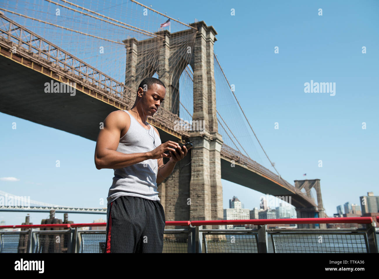Low angle view of man using phone against Brooklyn Bridge Stock Photo ...