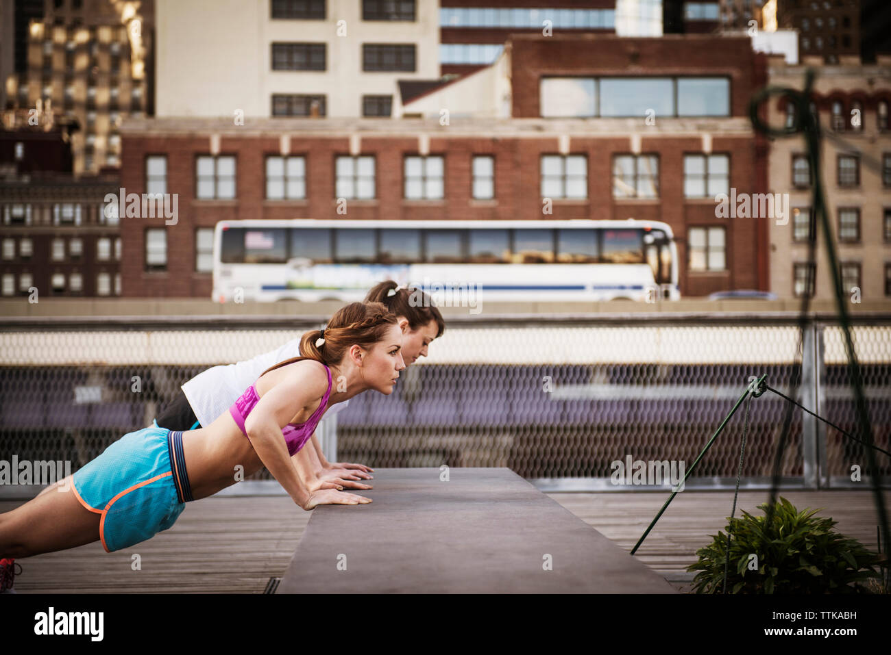 Friends doing push-ups at park against building in city Stock Photo - Alamy