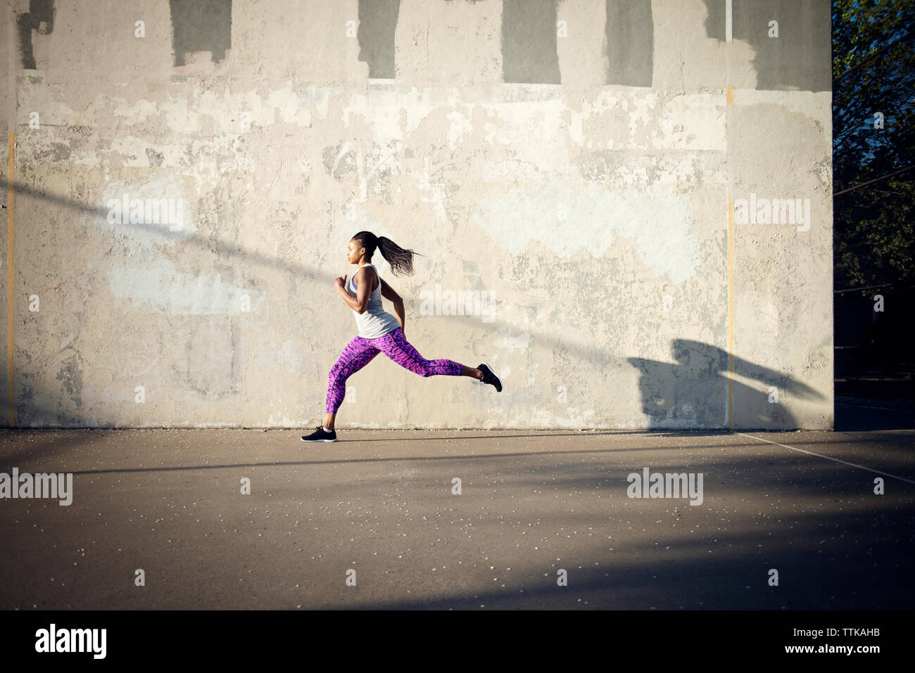 Woman jogging on street by wall Stock Photo - Alamy