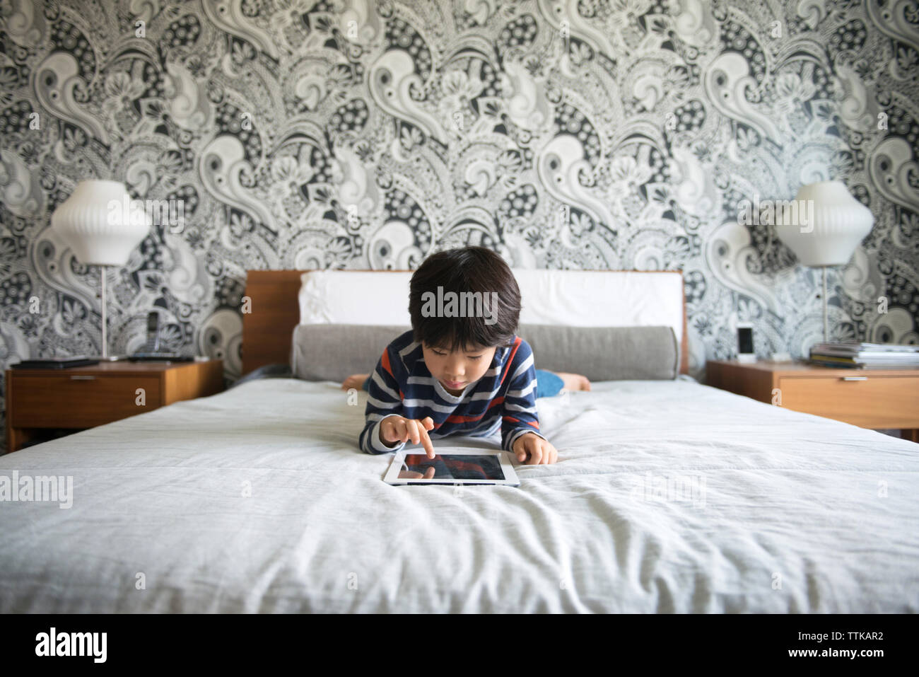 Boy lying on bed and using digital tablet in bedroom Stock Photo - Alamy