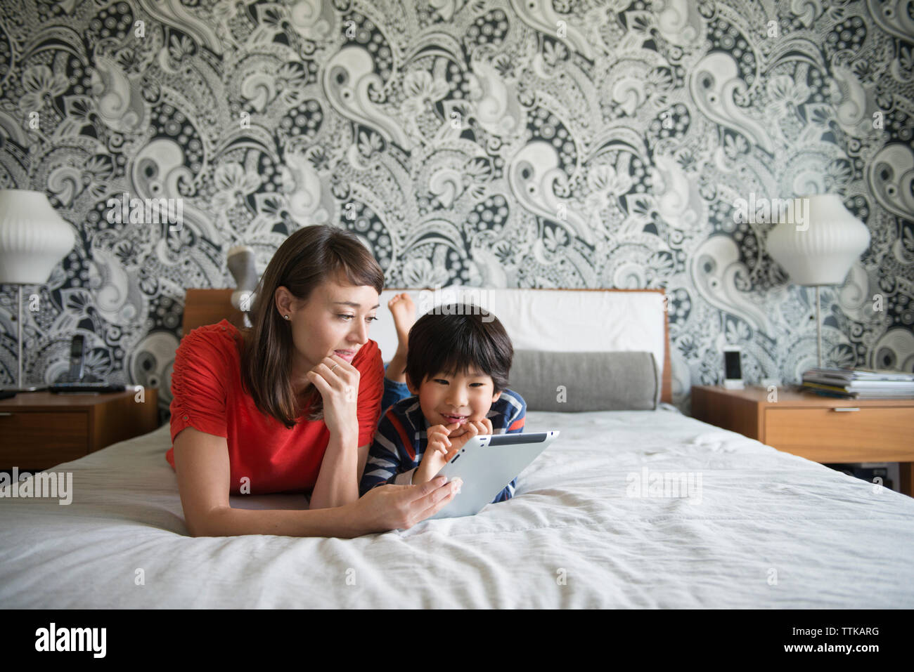 Mother and son using digital tablet while lying on bed Stock Photo - Alamy