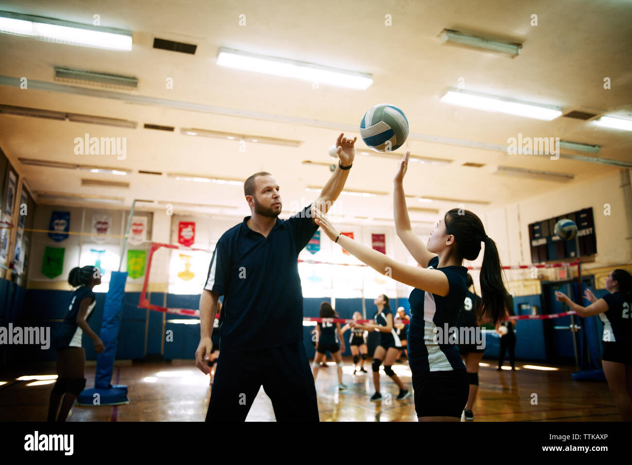 Male coach teaching volleyball to teenage girl Stock Photo - Alamy