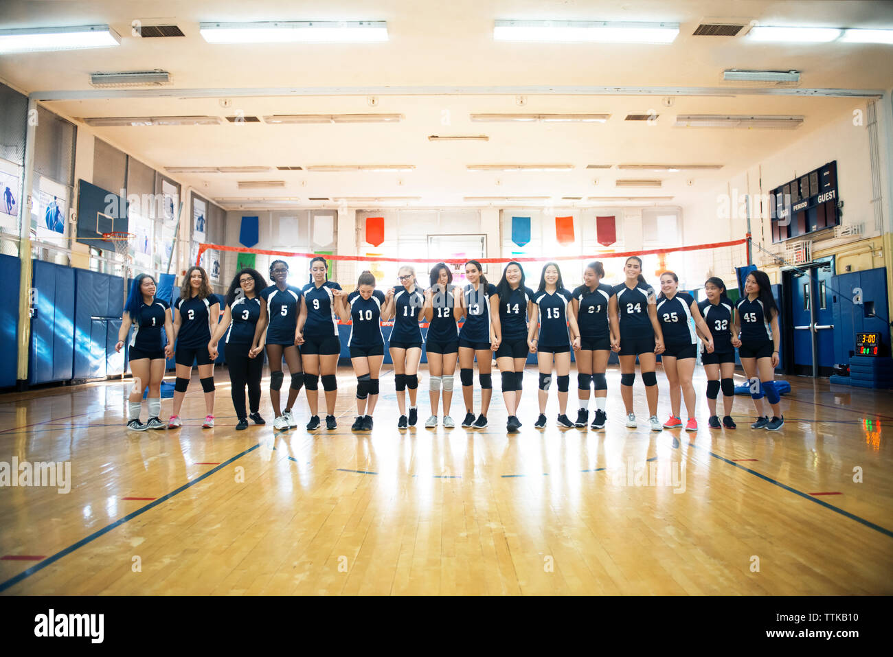 Front view of female team standing with arms around in volleyball Stock ...