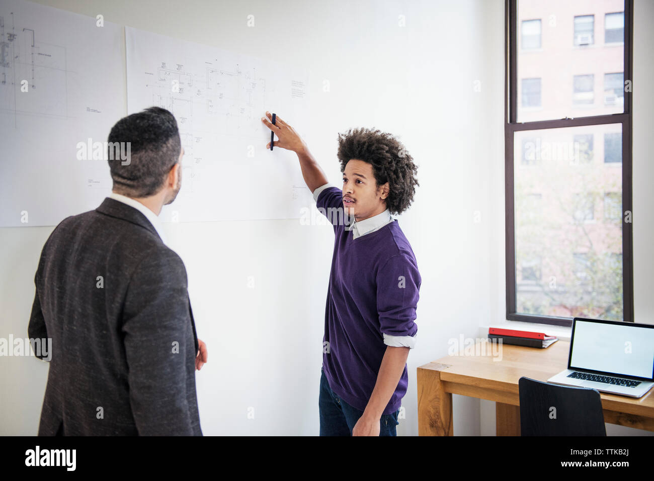 businessman explaining chart to colleague while standing in creative ...