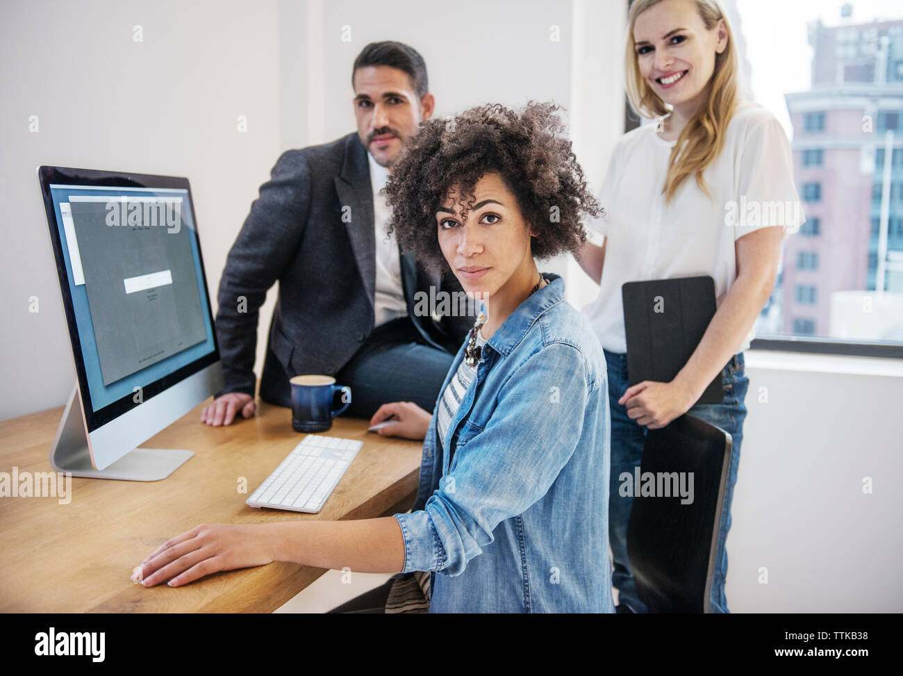 Portrait of confident business people using computer at desk in office ...