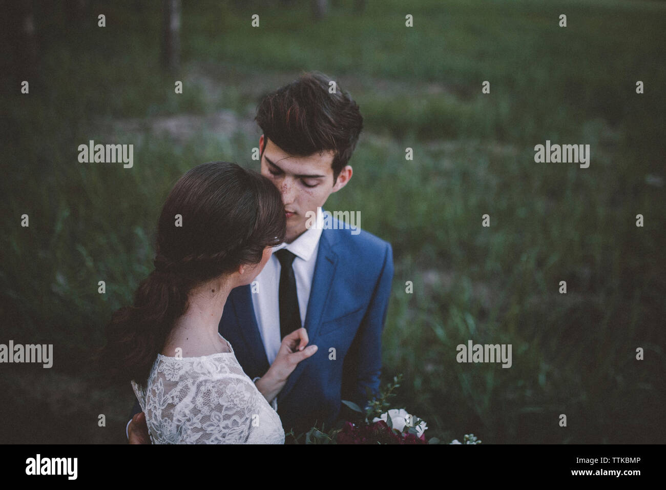 High angle view of bride with groom standing on grassy field in forest ...
