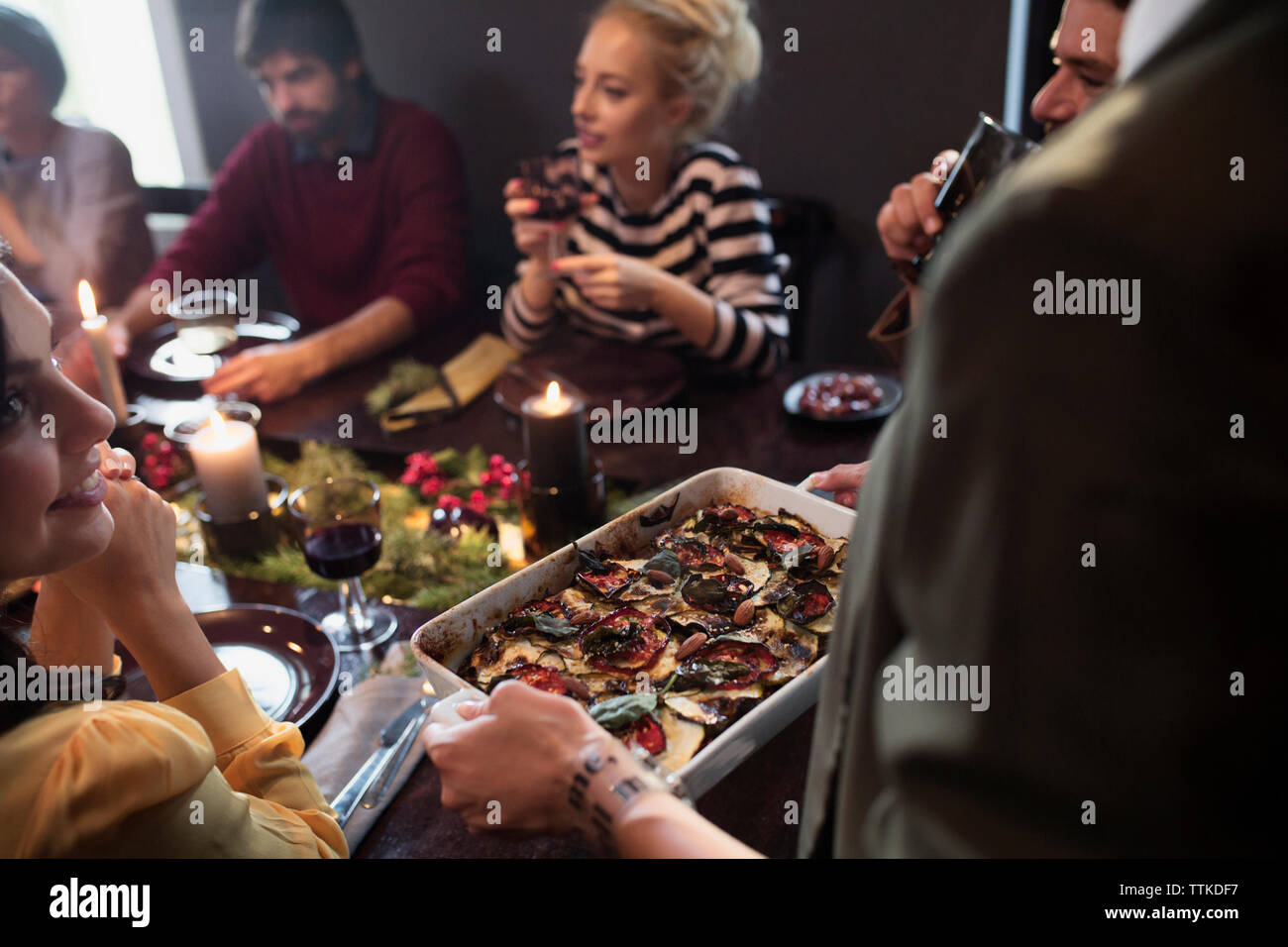 Woman serving food to happy friends at table during christmas party ...